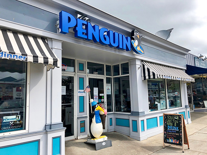 The Penguin's cheerful blue sign and tuxedoed mascot stand ready to welcome hungry beachgoers&mdash;like a breakfast ambassador promising morning delights just steps from the sand.