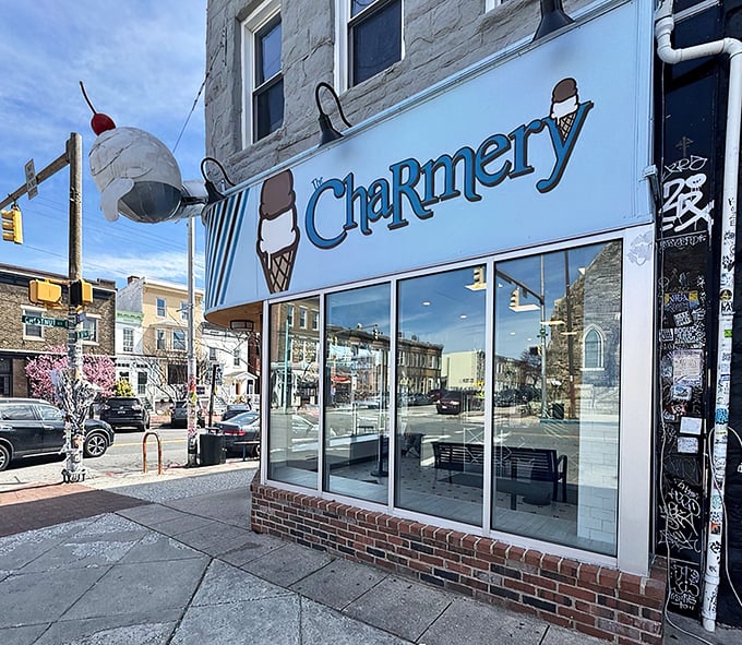 The corner shop that launched a thousand cravings. The Charmery's blue-striped awning and iconic ice cream cone logo beckon from Hampden's bustling Avenue.