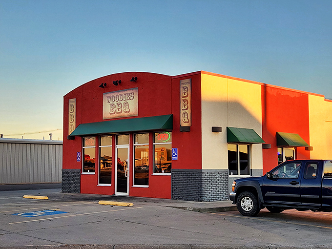 The bright red exterior of Woodies BBQ stands like a beacon for hungry travelers, promising smoky delights within those humble walls.