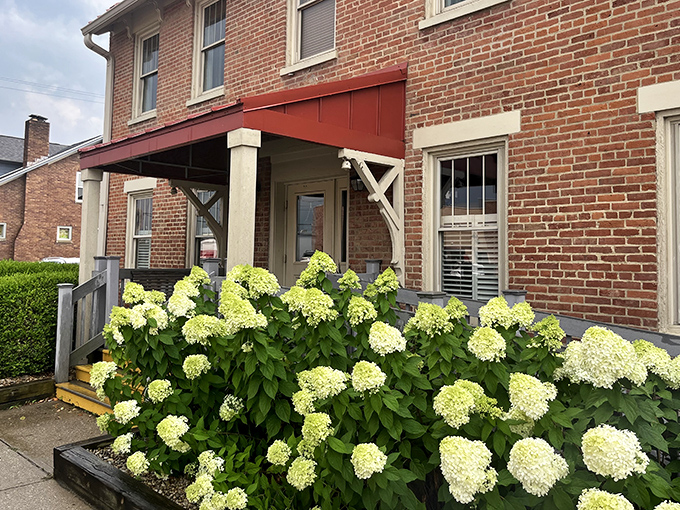 The historic brick exterior of Old Canal Smoke House welcomes you with its charming red awning and flower boxes&mdash;like a barbecue beacon calling you home.