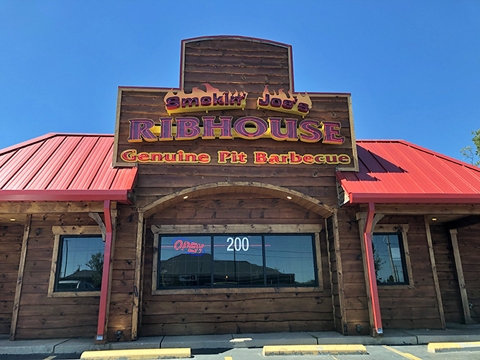 The red-roofed wooden exterior of Smokin' Joe's stands like a barbecue beacon in Rogers, promising smoky treasures within. A full parking lot never lies.
