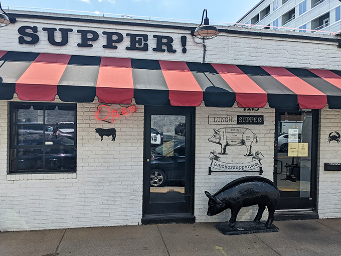 The iconic white brick exterior of LUNCH.SUPPER! with its jaunty red and black awning promises Southern comfort before you even step inside.