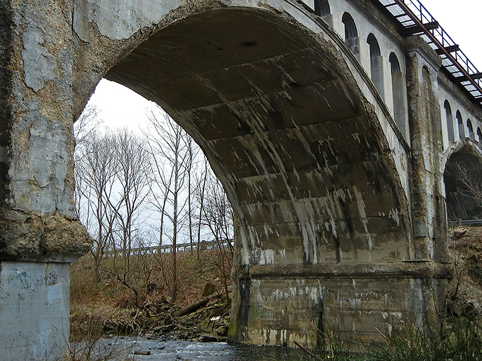 The weathered arches of Avon's Haunted Bridge stand sentinel against an autumn sky, where concrete and legend have intertwined for generations.