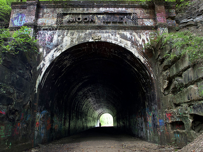 Nature reclaims what man abandoned at Moonville Tunnel, where vibrant greenery frames this portal to the past. The perfect backdrop for both daytime adventures and nighttime frights.
