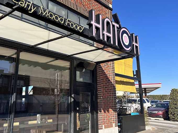 The golden glow of Hatch's signage beckons like a breakfast lighthouse. Those blue chairs aren't just seating—they're your front-row tickets to the morning's main event.