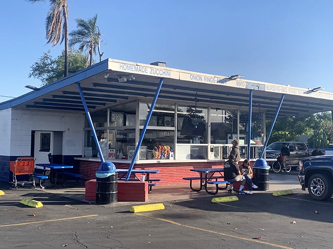 The blue-striped awning of George's Drive-In stands like a beacon of burger paradise against the California sky, promising delicious nostalgia with every order.
