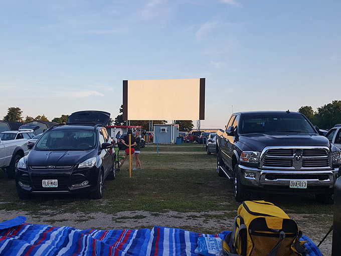 Cars aligned in perfect movie-watching formation as dusk approaches. Some visitors come early to claim prime viewing spots with blankets and lawn chairs.