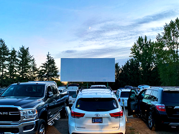 As twilight descends, cars line up facing the massive white screen, where cinematic dreams come alive under Oregon's star-studded sky.