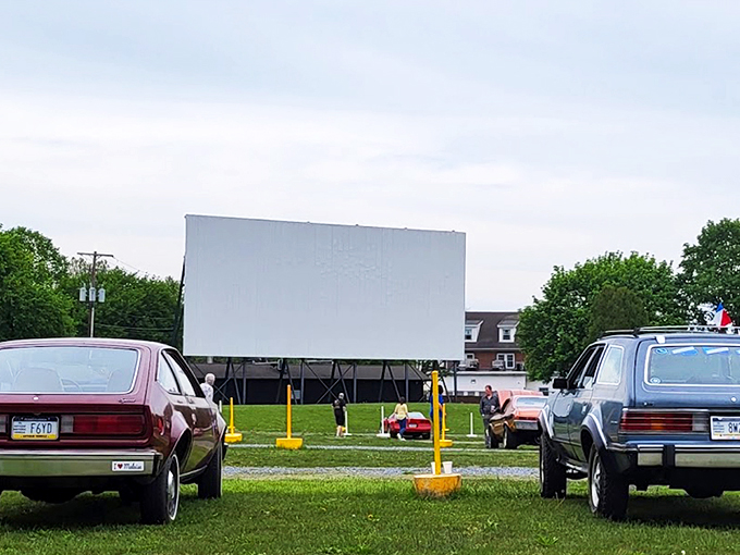 Twilight magic unfolds as cars line up facing the massive white screen, nature providing the perfect backdrop for cinematic adventures.