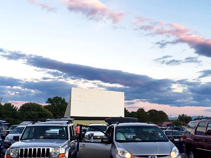 Twilight magic unfolds as cars gather beneath a pastel sky, the massive white screen waiting to transport viewers to another world.