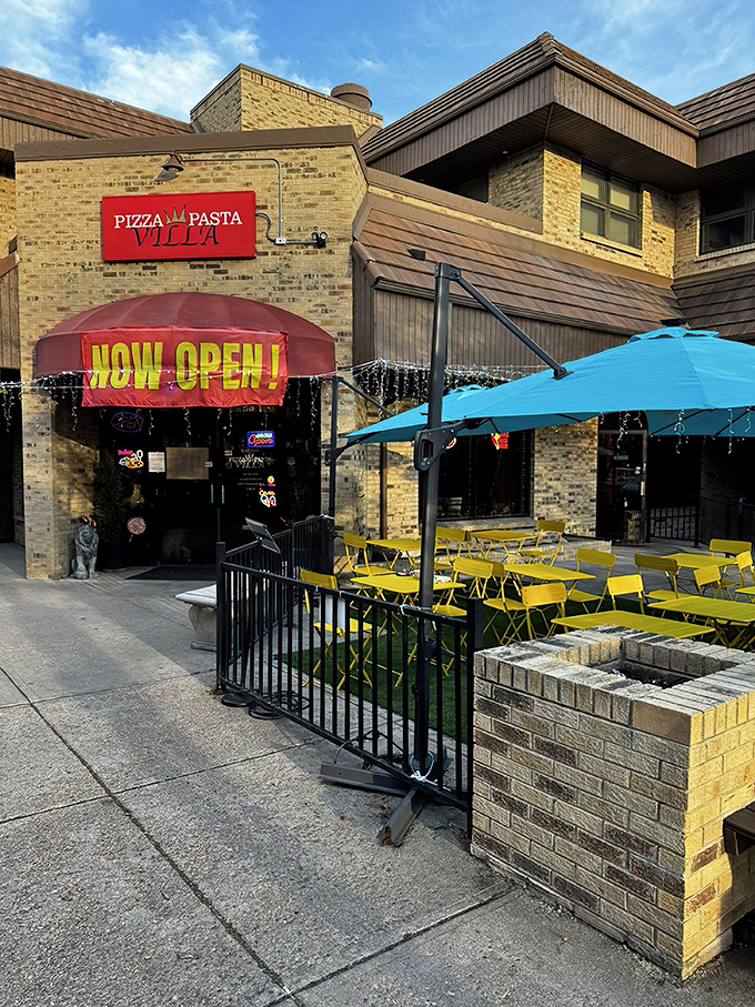 The inviting brick exterior with its cheerful red awning promises Italian delights within. Purple flowers and lush greenery create a welcoming oasis in Denver.