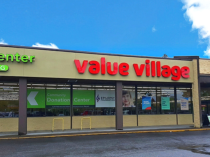 The iconic red Value Village sign beckons like a lighthouse for bargain hunters navigating the sea of retail sameness.