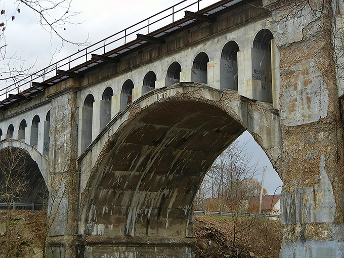 The weathered arches of Avon's Haunted Bridge stand sentinel against an autumn sky, where concrete and legend have intertwined for generations.