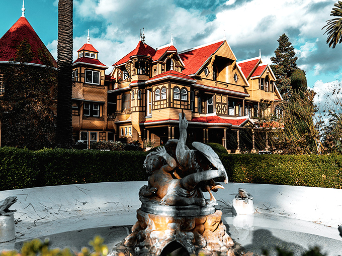 The Winchester Mystery House looms against the sky, its Victorian fa&ccedil;ade hiding countless architectural oddities that would make Escher scratch his head in confusion.