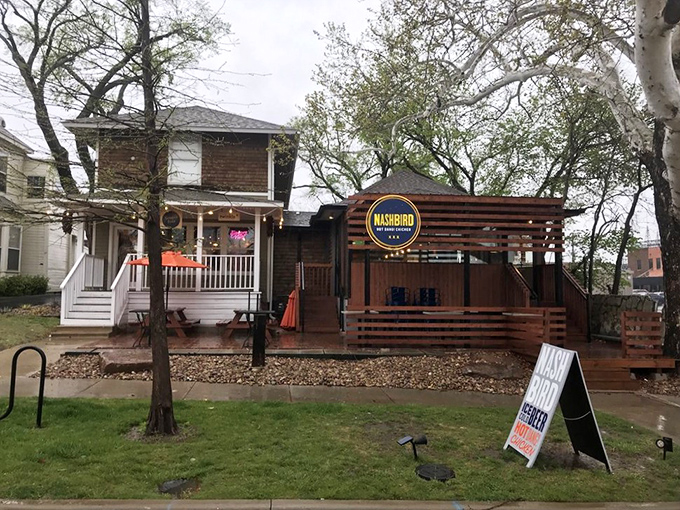 NASHBIRD's charming converted house exterior beckons with its wooden deck and bright signage—like a Southern porch that happens to serve life-changing chicken.