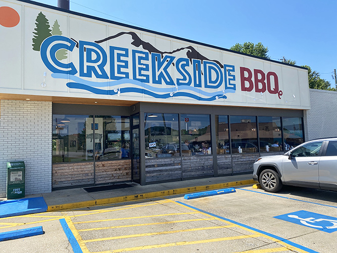 The blue and red Creekside BBQ sign beckons like a lighthouse for the hungry, promising smoky treasures inside this Pelham landmark.