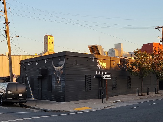 The unassuming exterior of Horn BBQ in Oakland &ndash; where that bold white lettering against dark panels is the architectural equivalent of a whisper about the best-kept secret in town.