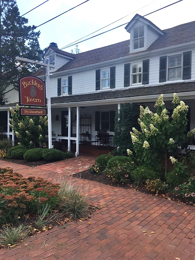 A storybook come to life! Buckley's Tavern's charming exterior beckons with its white clapboard siding, inviting porch, and lush gardens. It's the culinary equivalent of a warm hug.