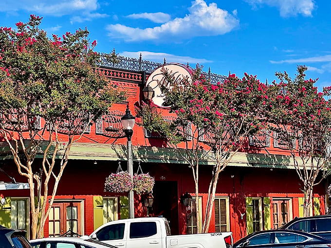 The vibrant red exterior of Mike's Place, framed by blooming crepe myrtles, stands as Conway's culinary beacon for seafood lovers.