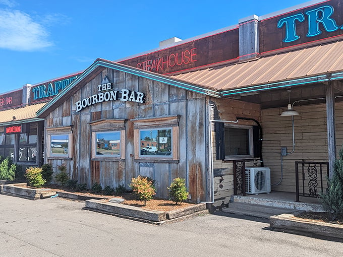 The rustic wooden facade of Trapper's beckons like an old friend, promising comfort food with Cajun flair beneath those neon signs.