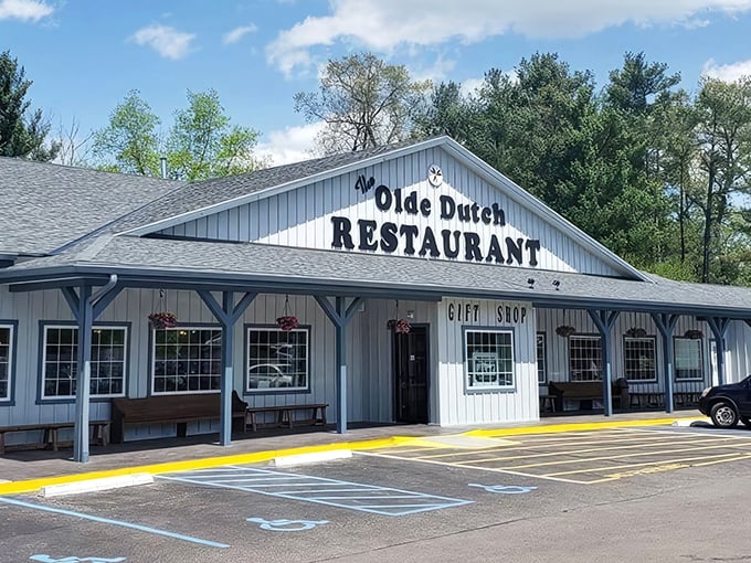 Welcome to comfort food paradise! The blue-sided exterior of Olde Dutch Restaurant in Logan invites hungry travelers with its charming porch and promise of home-cooked delights.