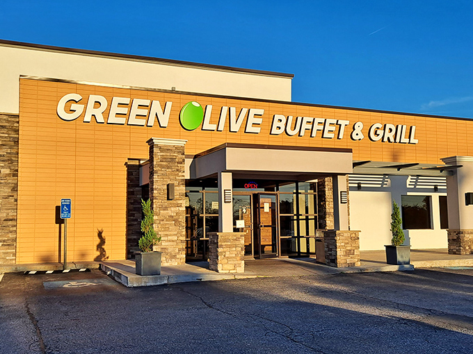 The golden-orange facade of Green Olive Buffet stands like a beacon to hungry travelers. Stone accents and modern signage promise culinary adventures within.