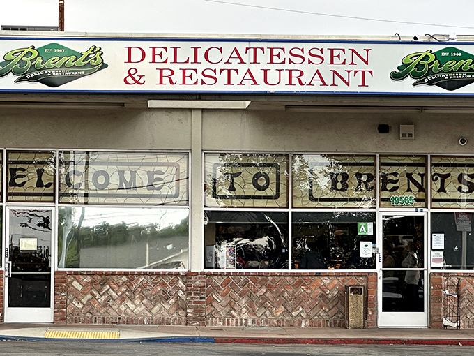 The classic storefront of Brent's Deli beckons with its nostalgic charm. Those red umbrellas aren't just for show&mdash;they're gateways to sandwich paradise.