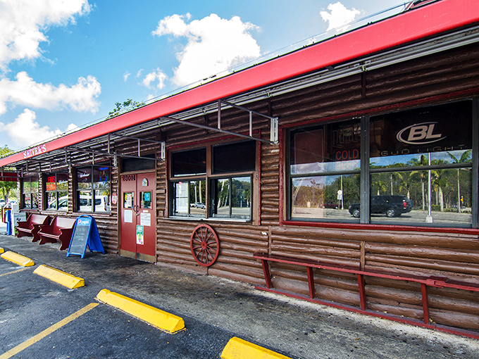 The rustic log cabin exterior of Shiver's BBQ stands as a beacon of smoky promise with its distinctive red trim and wooden fa&ccedil;ade.