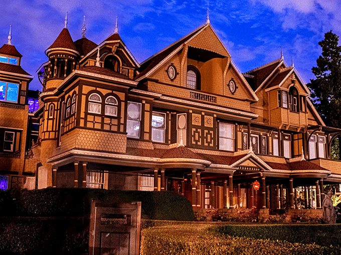 The Winchester Mystery House looms against the night sky, its Victorian fa&ccedil;ade hiding countless architectural oddities that would make Escher scratch his head in confusion.