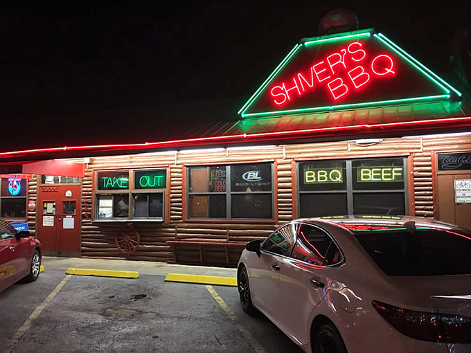 The rustic log cabin exterior of Shiver's BBQ stands as a beacon of smoky promise with its distinctive red trim and wooden fa&ccedil;ade.