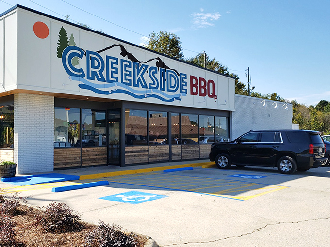 The blue and red Creekside BBQ sign beckons like a lighthouse for the hungry, promising smoky treasures inside this Pelham landmark. 