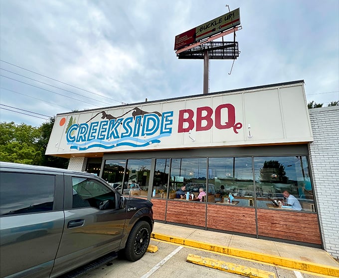 The blue and red Creekside BBQ sign beckons like a lighthouse for the hungry, promising smoky treasures inside this Pelham landmark.