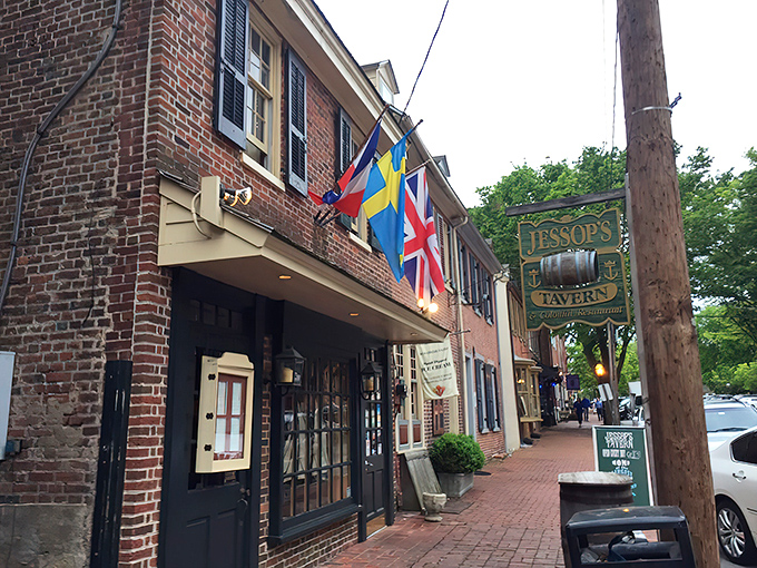 History flies proudly outside Jessop's Tavern, where international flags flutter above brick-lined streets that have witnessed centuries of American stories.