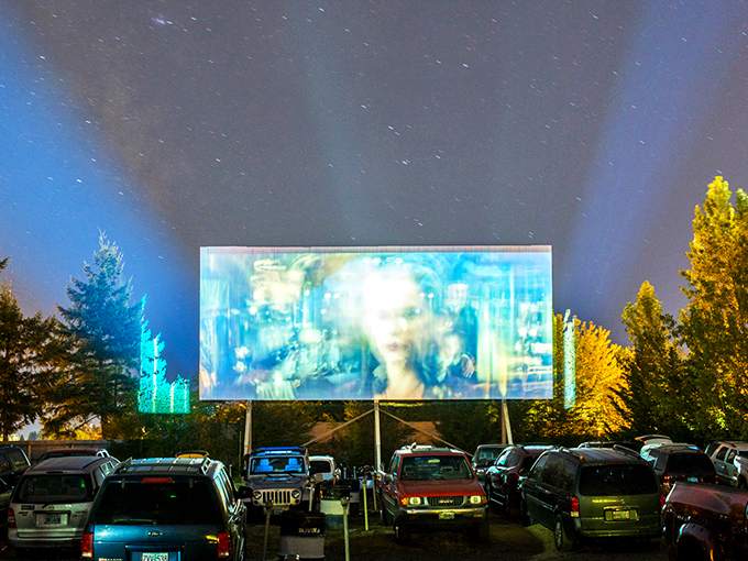 As twilight descends, cars line up facing the massive white screen, where cinematic dreams come alive under Oregon's star-studded sky. 
