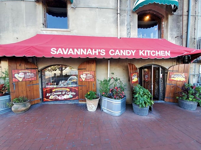 The iconic red awning of Savannah's Candy Kitchen beckons like a sweet siren call on River Street. Rustic wooden doors and lush planters create the perfect entrance to sugar paradise.