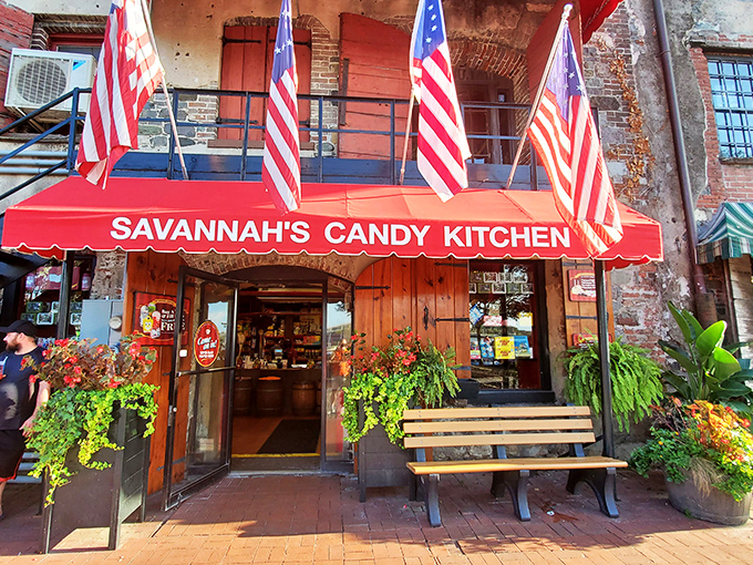 The iconic red awning of Savannah's Candy Kitchen beckons like a sweet siren call on River Street. Rustic wooden doors and lush planters create the perfect entrance to sugar paradise.