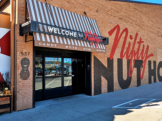 The brick facade of Nifty Nut House stands like a temple to temptation, its bold red script promising sweet adventures within. 