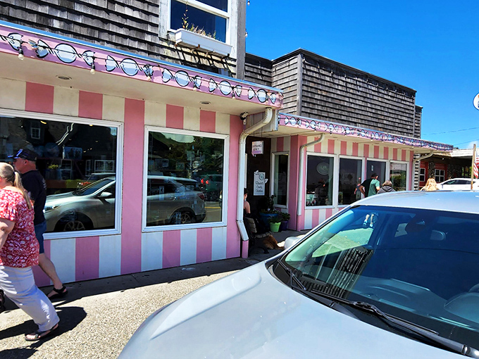 The pink and white striped façade of Bruce's Candy Kitchen stands out like a Wes Anderson film set come to life in Cannon Beach's coastal landscape.