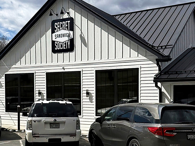 The charming white farmhouse exterior of Secret Sandwich Society stands like a beacon of hope for hungry travelers. Sandwich salvation awaits inside.