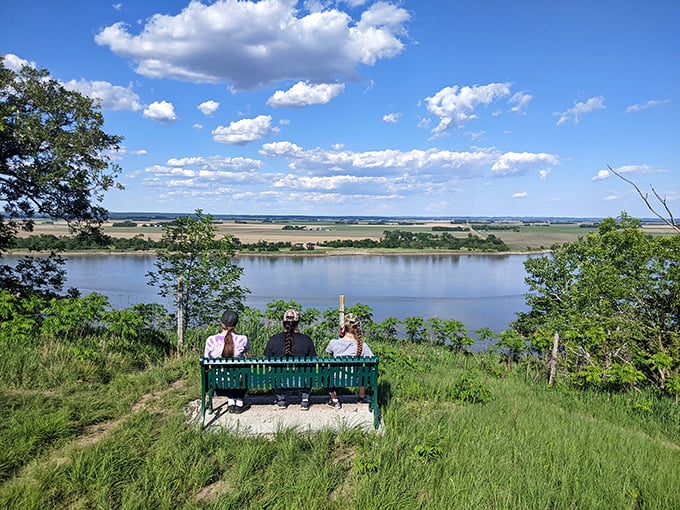 Friends are gathered on this green bench to enjoy a stunning view of the Missouri River.