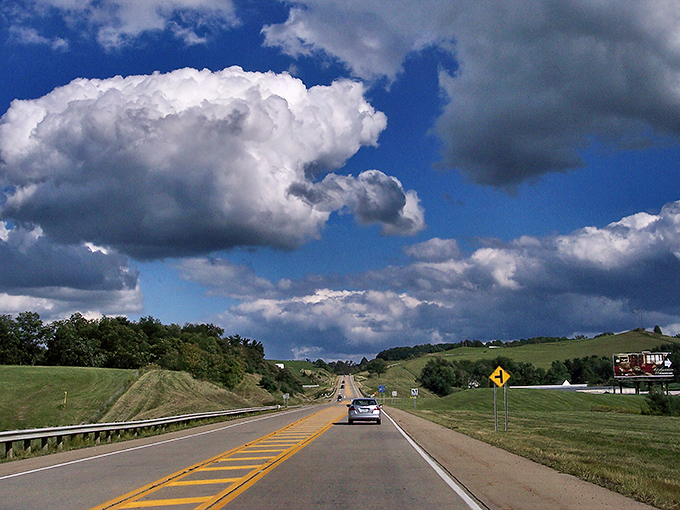 The open road stretches before you like nature's welcome mat, with clouds performing their own version of Cirque du Soleil overhead.