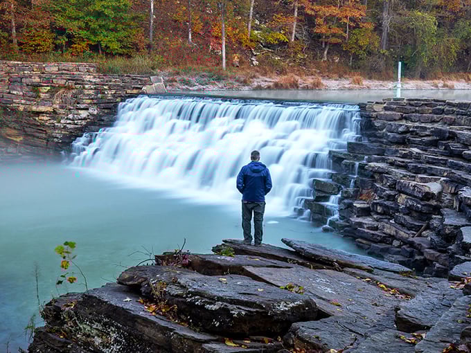 Nature's perfect postcard moment: a rustic wooden bridge leads you between cascading waterfalls, promising adventure with every step into this emerald paradise.
