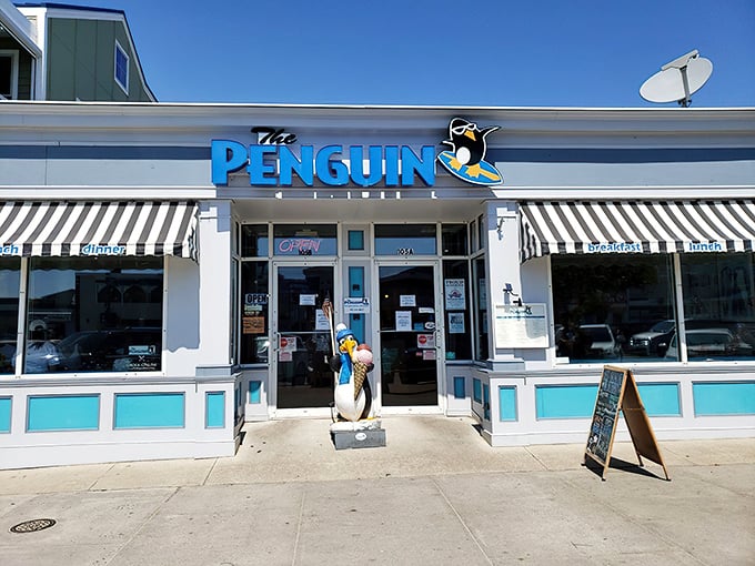 The Penguin's cheerful blue sign and tuxedoed mascot stand ready to welcome hungry beachgoers&mdash;like a breakfast ambassador promising morning delights just steps from the sand.