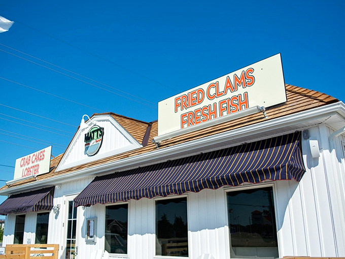 The classic white clapboard exterior with bold signage promising "FRIED CLAMS" and "FRESH FISH" is like a siren song to seafood lovers cruising coastal Delaware.