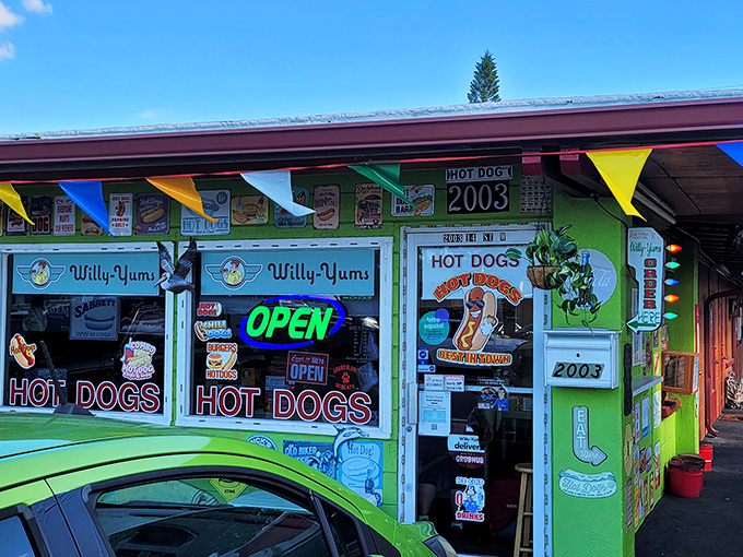 The lime-green beacon of Willy-Yums stands out like a culinary lighthouse, complete with festive pennant flags and enough "HOT DOG" signs to leave zero doubt about what's cooking inside.
