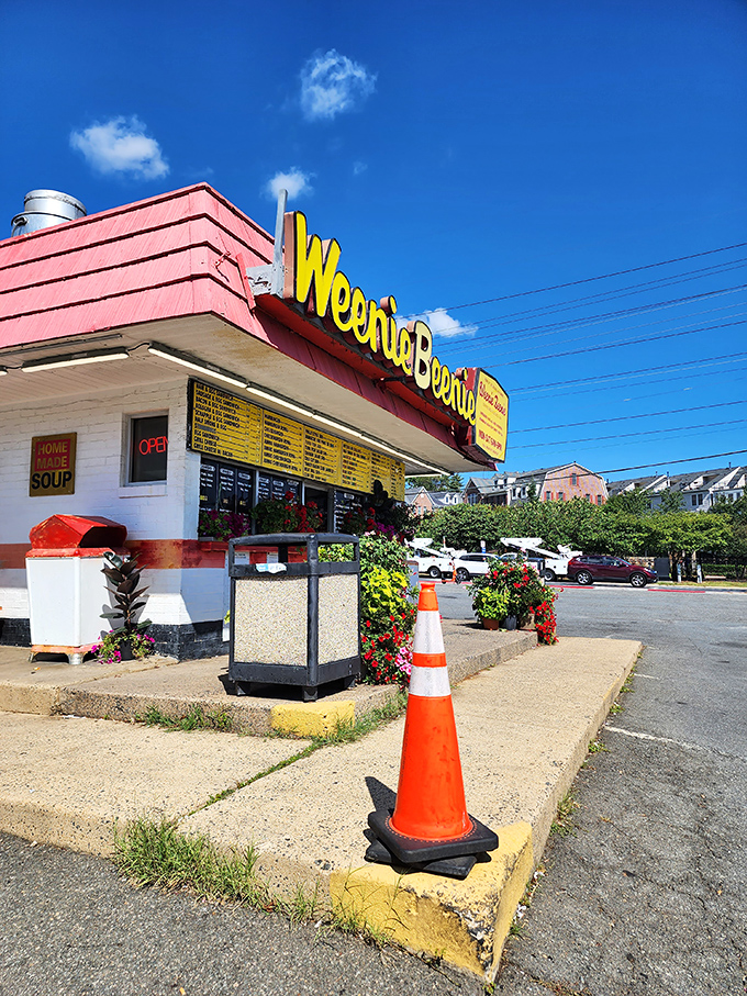The iconic pink-and-yellow Weenie Beenie stands proudly against a blue Virginia sky, like a time capsule of American roadside charm waiting to be discovered.
