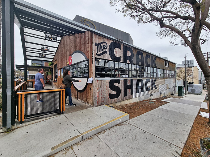 The rustic-industrial exterior of The Crack Shack beckons like a chicken-lover's mirage in Little Italy, where casual meets culinary genius under the San Diego sun.