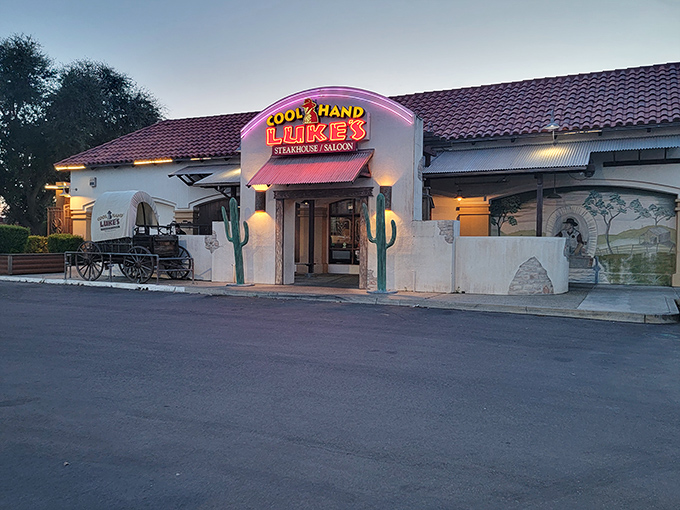 
The Western-themed exterior of Cool Hand Luke's beckons with its iconic cactus sentinels and vintage wagon&mdash;like stepping onto a movie set where dinner is the star attraction.