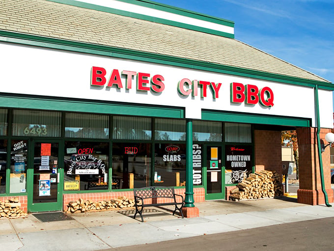 The unassuming storefront of Bates City BBQ, where stacked firewood isn't decor&mdash;it's a promise of smoky delights waiting inside.