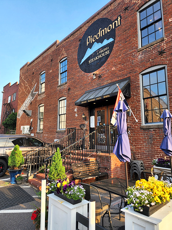 The historic brick facade of Piedmont Steakhouse welcomes you with understated elegance. Those bright blue planters aren't just decoration&mdash;they're your first hint that something special awaits inside.